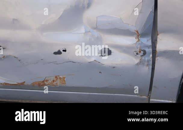 Close-up view shows rust spots and dents on a car door caused by damage ...