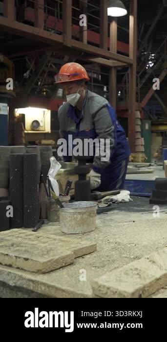 Foundry workers wearing masks and helmets are preparing molds for metal ...