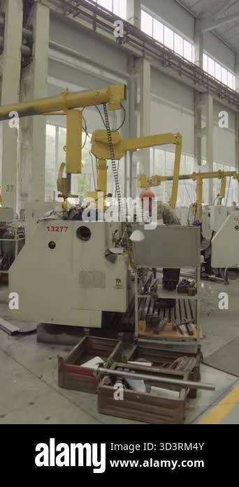 Factory worker operating a lathe machine, producing metal parts in a ...