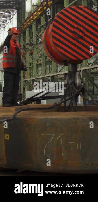 Engineers communicate using hand signals while working on a large metal ...