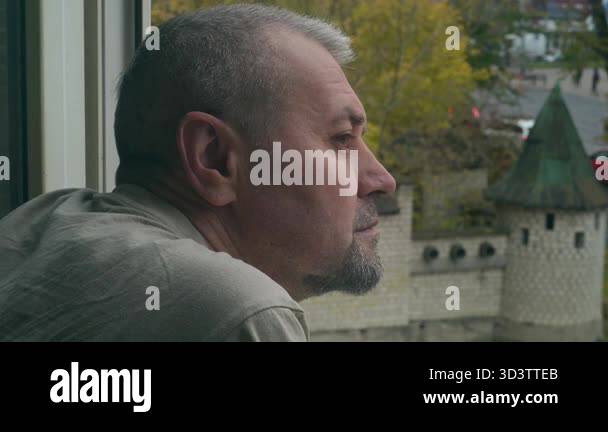 Sad man looking out the window. Man looking out over urban landscape ...