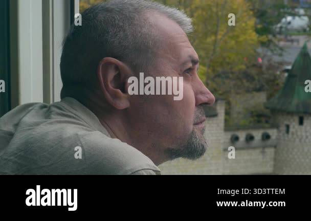 Sad man looking out the window. Man looking out over urban landscape ...