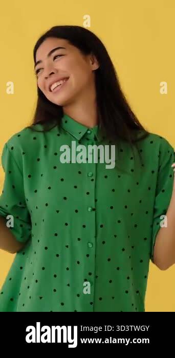 A happy asian woman in a green shirt is dancing, smiling, and grooving ...