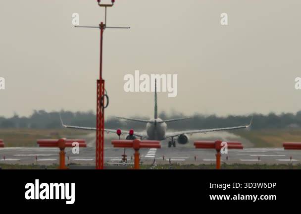 Rear view of jet aircraft on runway. Airliner gaining speed for takeoff ...