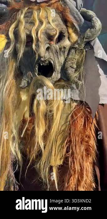 Close-up of creepy horned monster costume with long hair and skull mask ...