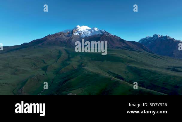 Lush, deep green valley with a stream leading up to majestic snow ...