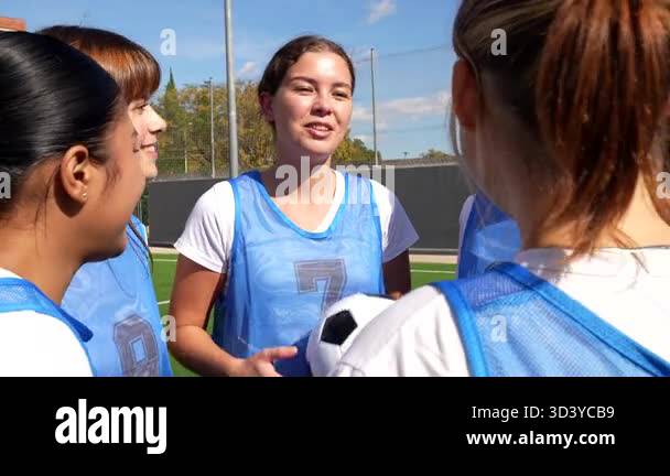 Young female soccer captain with a ball talking to her multiracial team ...