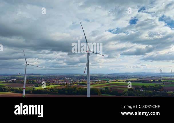 Tall wind turbines turn gently in the breeze surrounded by lush green ...