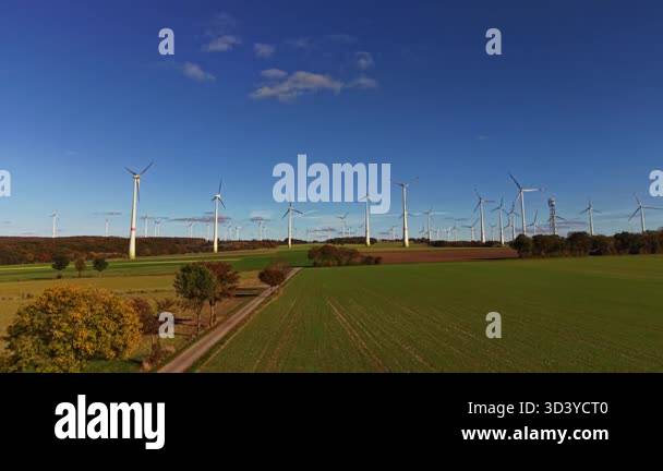 Numerous wind turbines stand tall on green fields gently rotating in ...