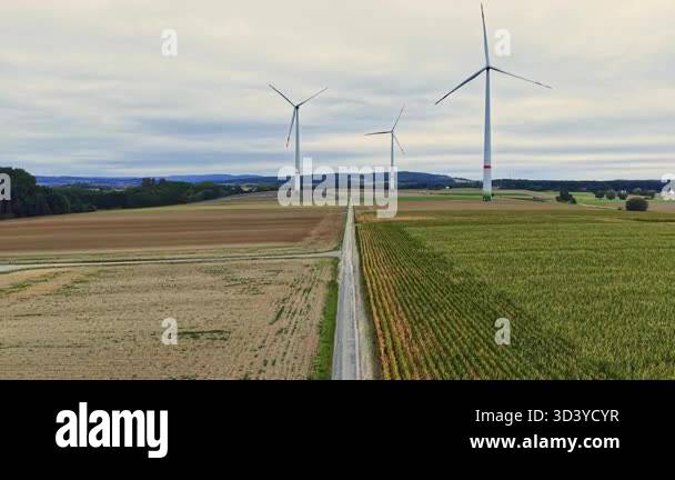 Four wind turbines rise above the rolling fields surrounded by lush ...
