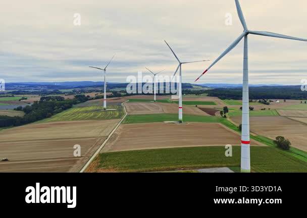Tall wind turbines turn gracefully in the light breeze surrounded by ...