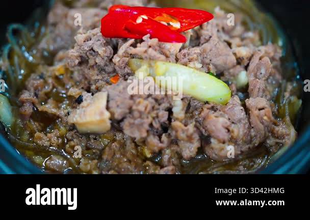 Thinly sliced beef is added to a bubbling pot of so-bulgogi in a ...