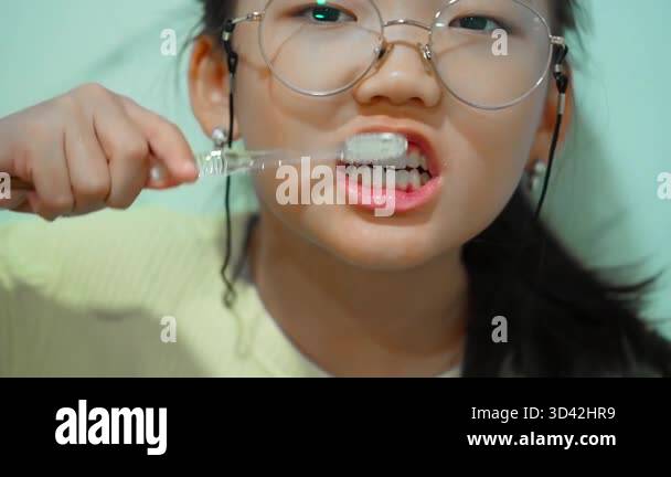 Young asian girl brushing her teeth with toothbrush, standing in ...