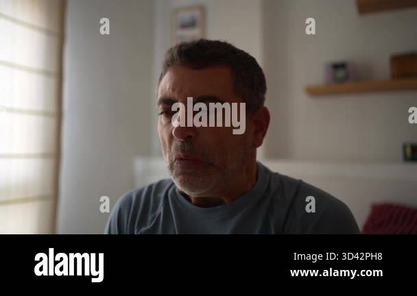 In a tranquil and serene indoor setting, a man sits quietly, deeply ...
