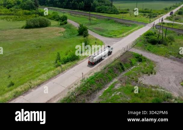 Fuel tanker truck drives on countryside road near railway crossing ...