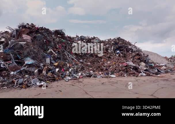 Large mound of scrap metal stands in recycling yard by cracked concrete ...