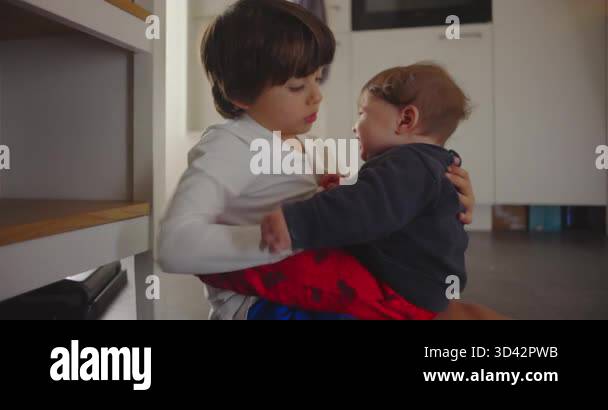 Older brother sitting on the kitchen floor holding his baby sibling ...