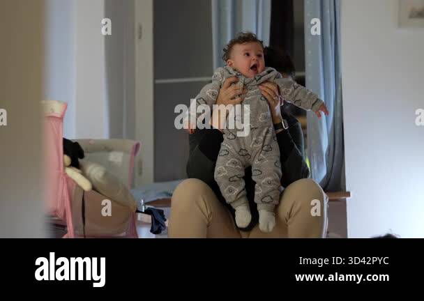 Parent lifting baby playfully in bedroom, both smiling and interacting ...