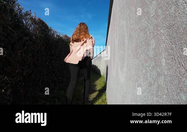 woman in beige jacket running along alley, caucasian woman with red ...