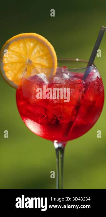 glass of fresh refreshing classic red campari cocktail against a green ...