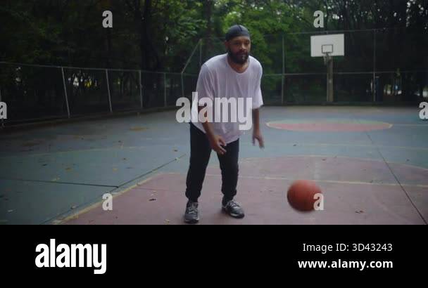 African descent man dribbling basketball between legs on outdoor urban ...