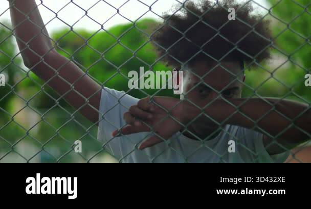 Young African American man resting arm on fence in moment of exhaustion ...