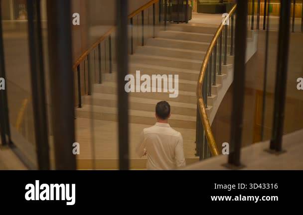 man descends staircase inside hotel, person walking down marble ...