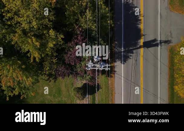Aerial drone view of an electric power line pole casting a long shadow ...