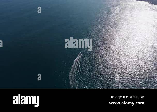 A boat moves swiftly over the sparkling sea, creating ripples as it ...