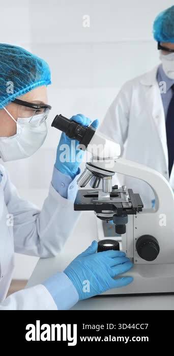 Two scientists in lab coats, face masks, and protective glasses ...