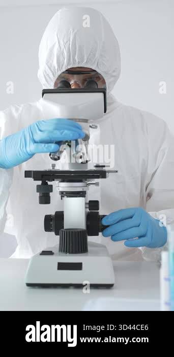 Medical virologist wearing a hazmat suit is working diligently with a ...
