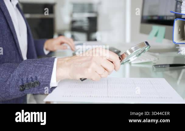 Professional accountant examining financial paperwork with a magnifying ...