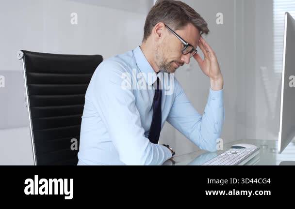 Businessman sitting at a desk in his office, suffering from a severe ...