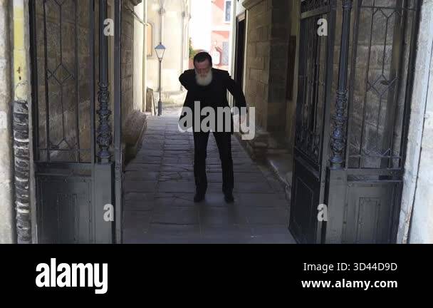 Old man with white beard walking through a narrow historic alley under ...