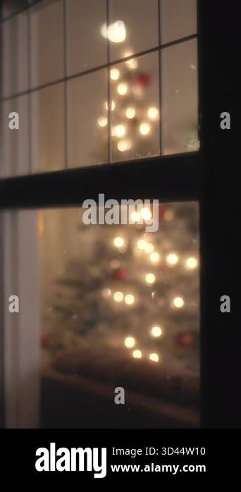 Christmas tree at home with snow falling outside, window view. Vertical ...