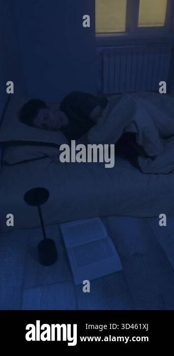 Man turns off night lamp after reading book and goes to sleep, showing ...