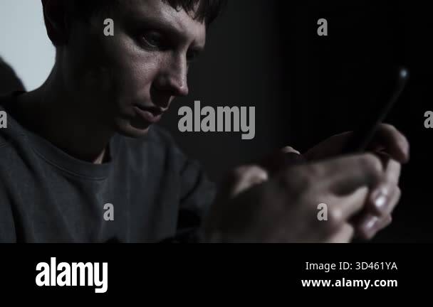 Man sits alone in the dark, focused on tense texting during ...