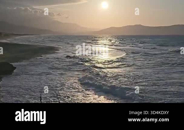 Golden hour view of the Mediterranean Sea waves crashing onto a sandy ...