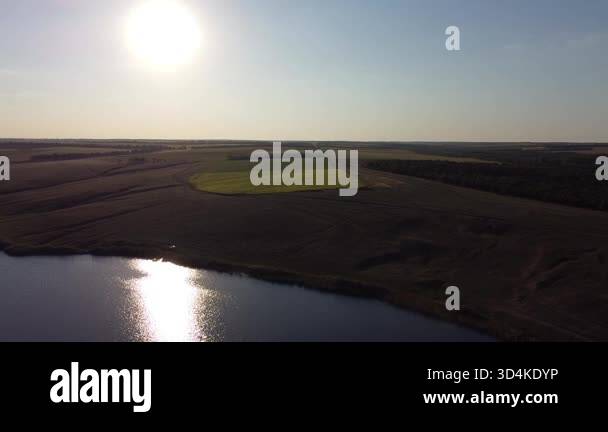 Drone flyover of a tranquil man-made lake and the surrounding farmlands ...