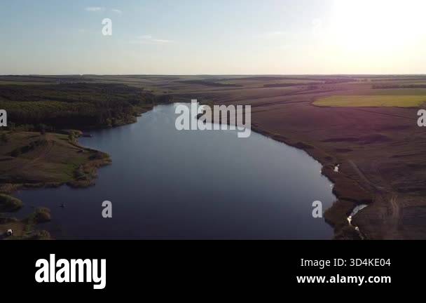 Drone flyover of a tranquil man-made lake and the surrounding farmlands ...