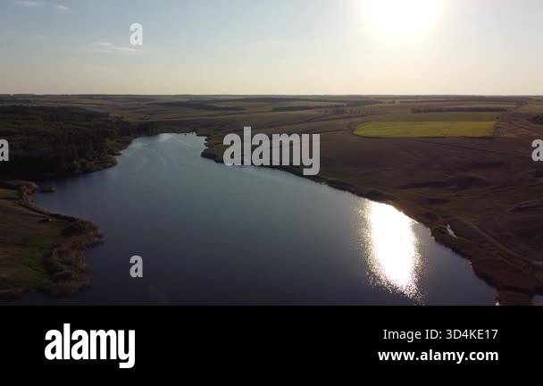 Drone flyover of a tranquil man-made lake and the surrounding farmlands ...