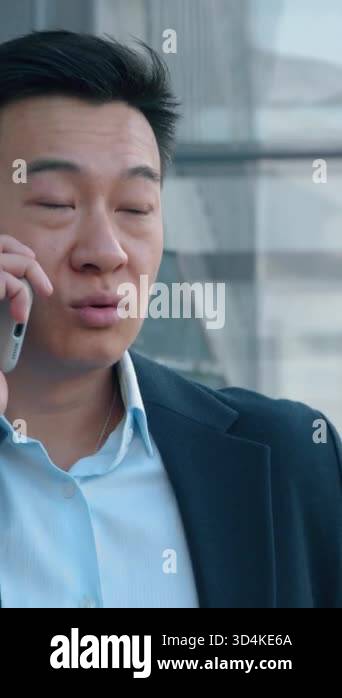 Smiling walking Asian middle-aged business man talking mobile phone ...