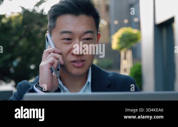 Happy smiling Asian business man talking mobile phone laptop using ...