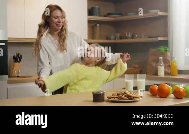 Caucasian happy family at kitchen at home laughing funny child girl with mother at dining table ...
