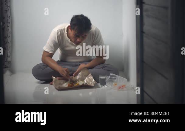 A homeless man is eating on the floor and leaves some of his food ...