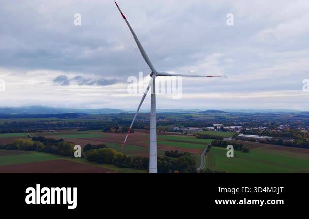 A tall wind turbine captures the wind's energy against a backdrop of ...