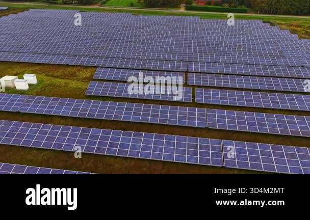 Rows of solar panels stretch across the green field, soaking up ...