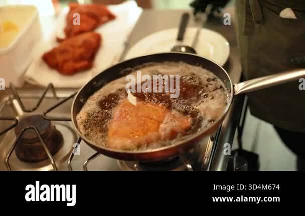Close-up video showing a cordon bleu frying in hot oil inside a pan ...