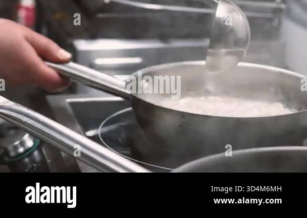 Preparing meal. Hot sauce. Chef hand adding ladle water to meal in ...