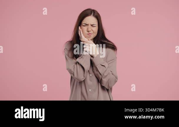 Pretty young woman with tooth pain on pink studio background. Toothache ...